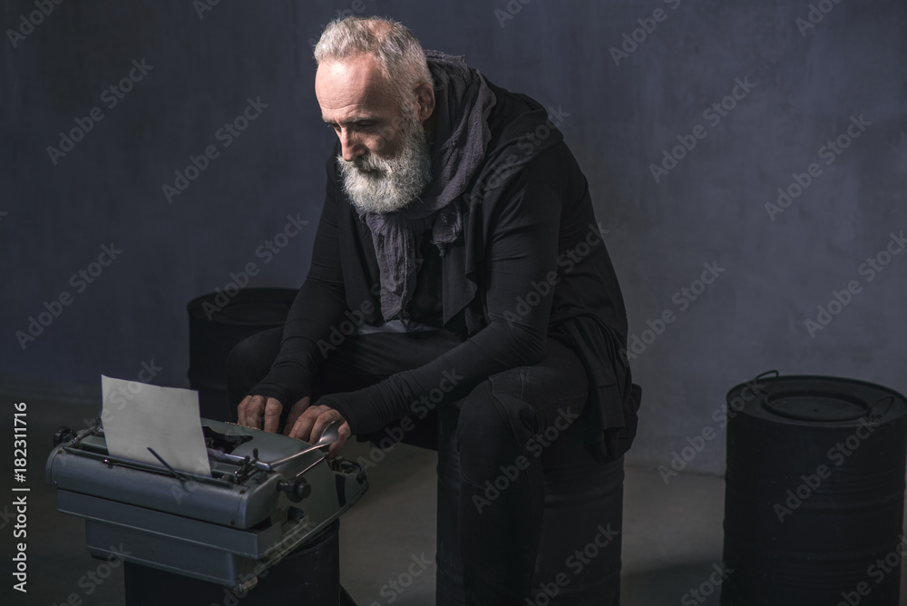 Stock-Foto „Side view serious unshaven old author typing in printing ...