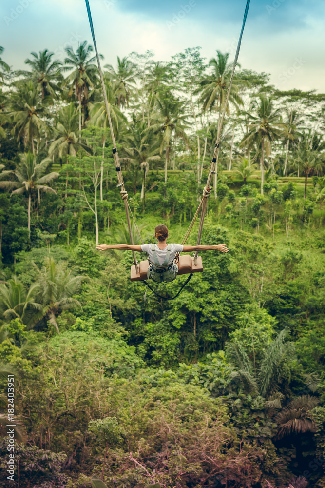 Young tourist woman swinging on the cliff in the jungle rainforest of a ...