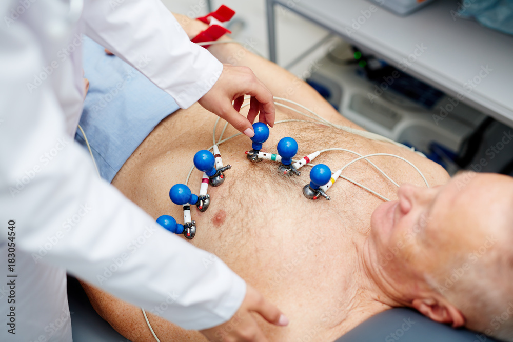 Cardiologist putting special equipment on chest of patient before ...