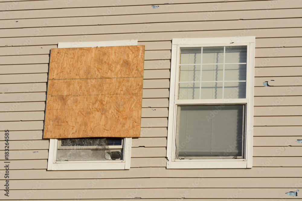 Boarded up window and hail storm damage on house siding and window ...
