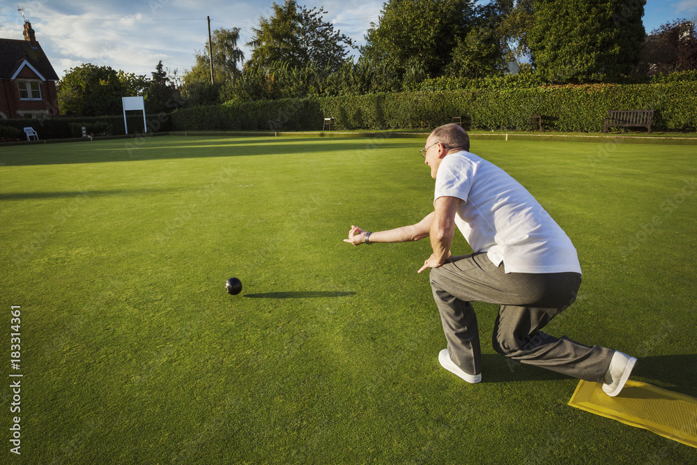 A lawn bowls player standing on a small yellow mat preparing to deliver ...