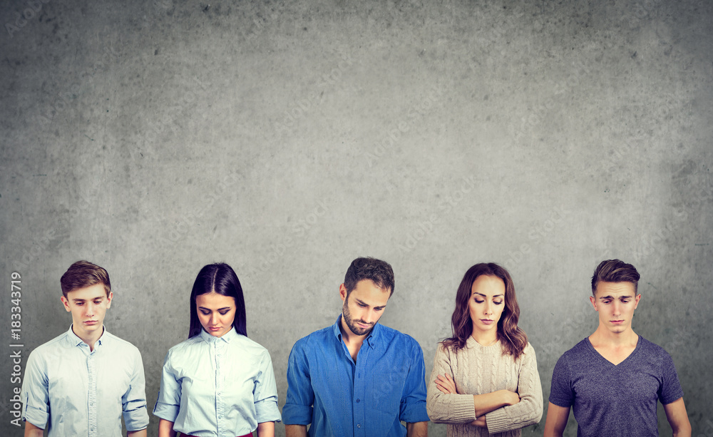 Group of sad unhappy people men and women standing against gray wall ...