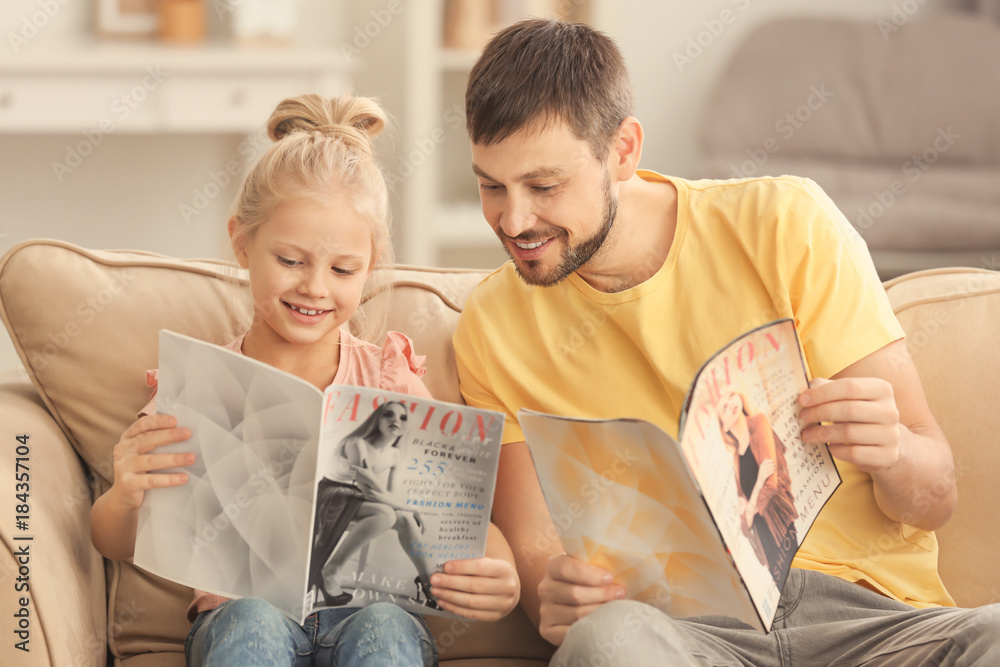 Cute little girl and her father reading magazines at home Stock Photo ...
