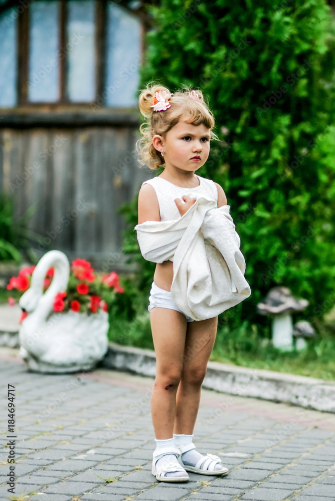 Zdjęcie bez tantiem: .The little girl raised her dress | Adobe Stock