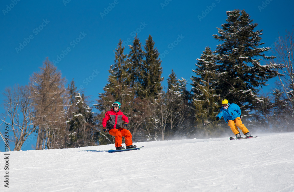 Male snowboarder riding on the snowy slope and professional skier ...