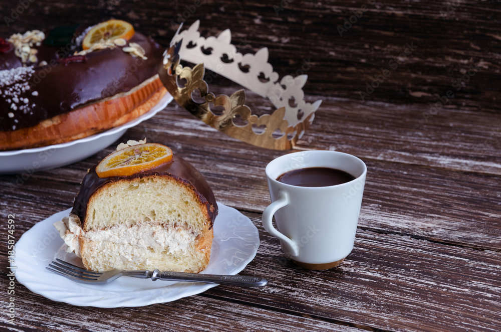 Roscon de reyes slice and cup of hot chocolate on wooden background ...