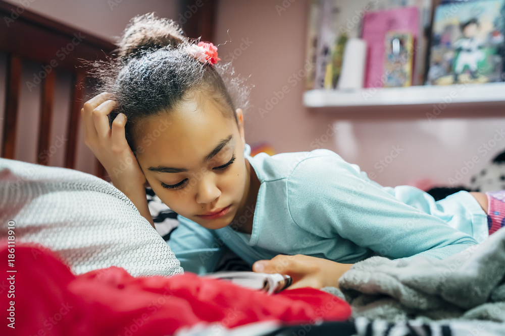 Tween girl reading book in bed Stock Photo | Adobe Stock