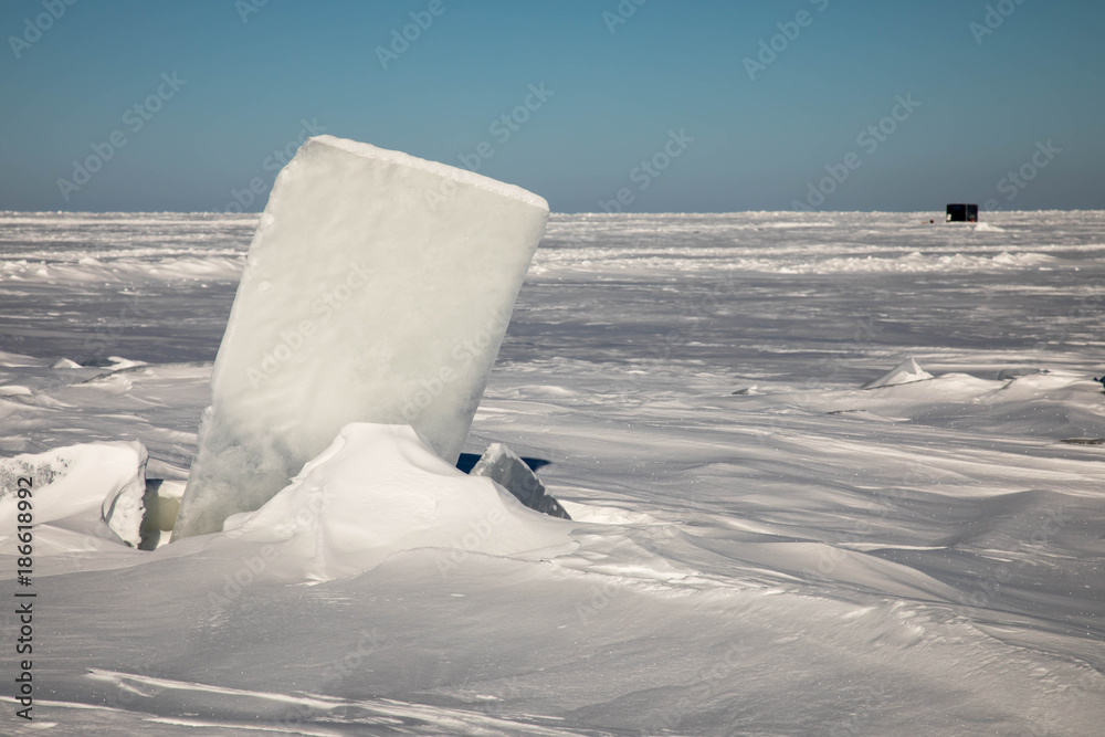 Slab of ice elevated from a pressure ridge and an ice shanty on Lake of ...