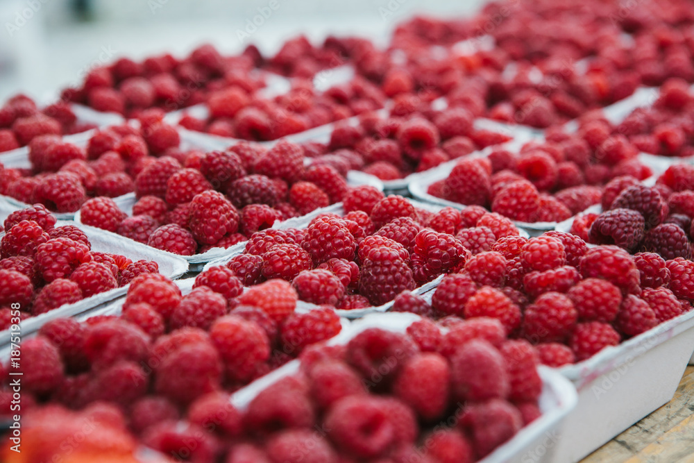 A lot of raspberries in containers on the table in a row. Useful food ...