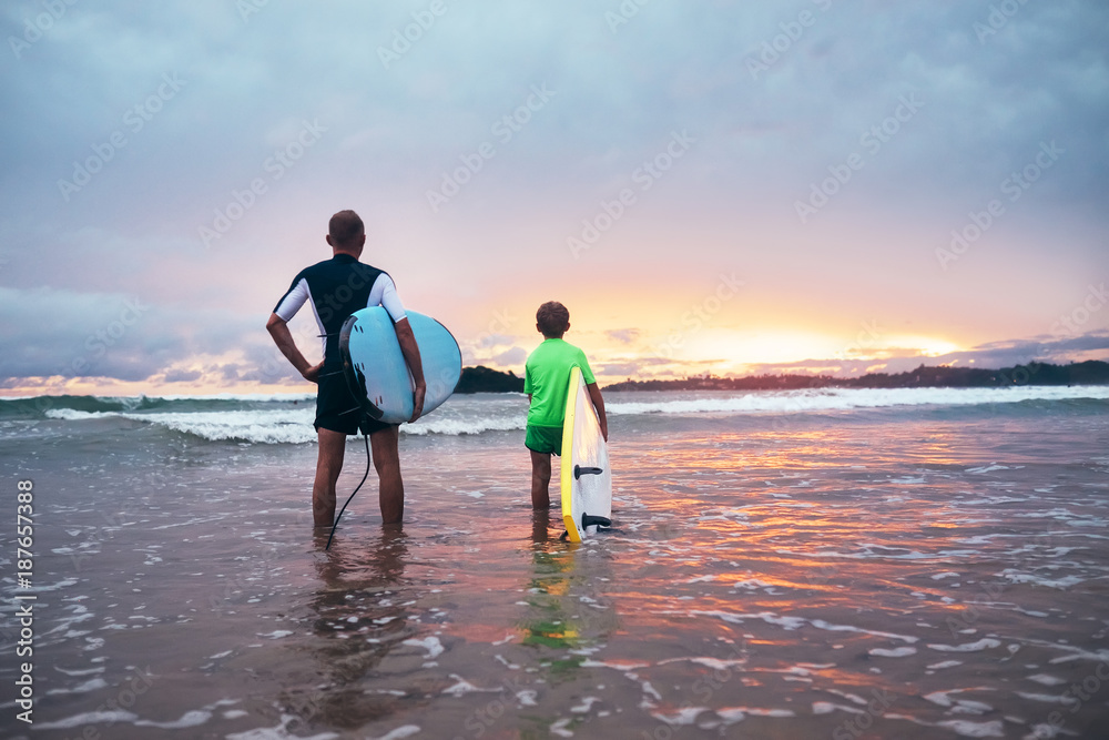 Father and son stand on the surf line with surf boards on sunset Stock ...