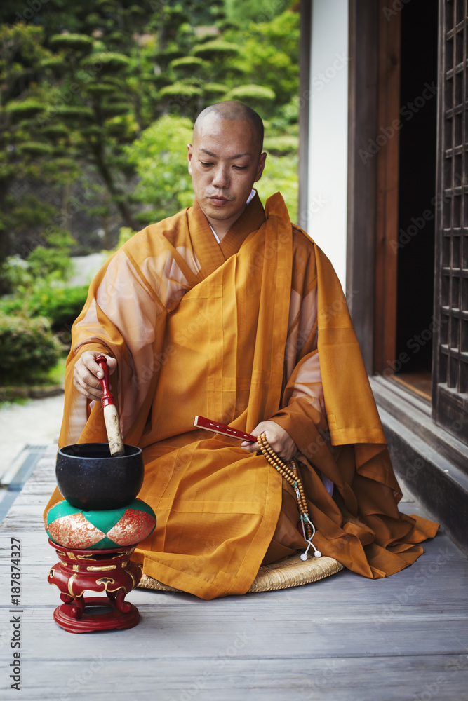 Buddhist monk with shaved head wearing golden robe sitting on floor ...