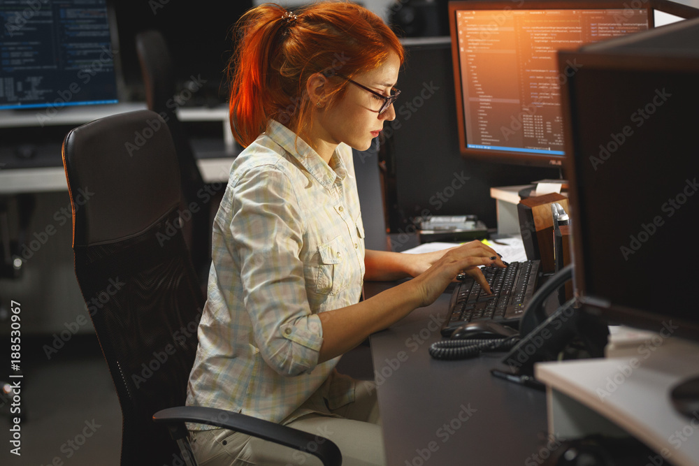 Late at night, a dedicated red hair female programmer works diligently ...