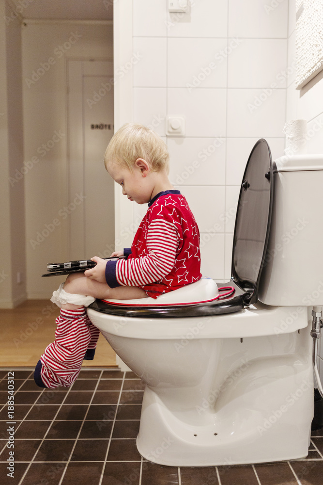 Little boy sitting on toilet in baby toilet seat Stock Photo | Adobe Stock