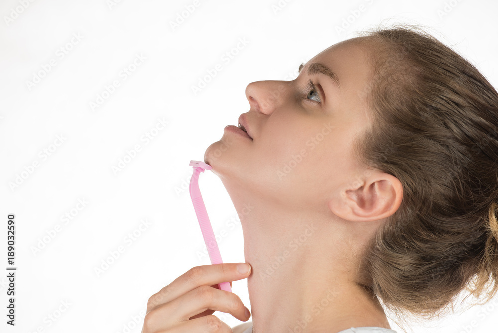 Young beautiful woman shaves a chin with a razor on a white background ...