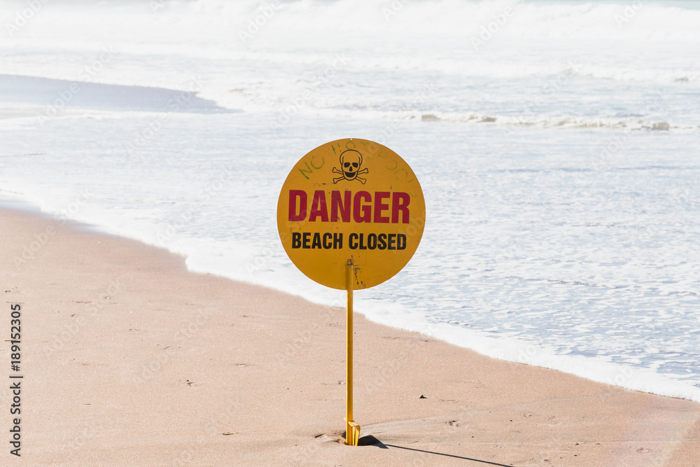 swimming prohibited, beach closed warning sign on a beach with blue ...