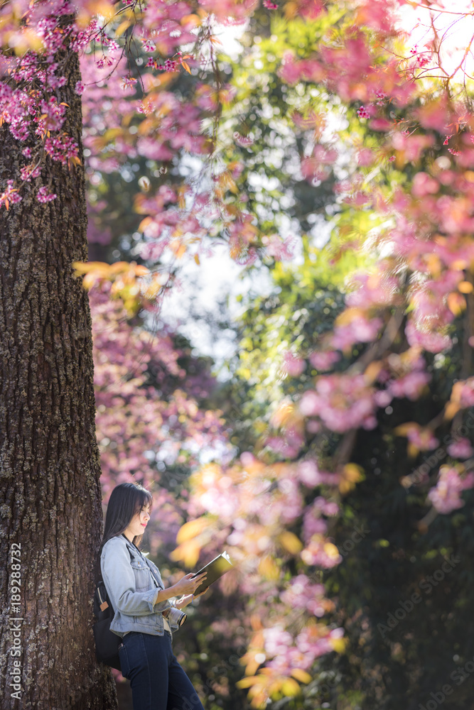Beautiful young woman standing under big tree on sunny spring day in ...