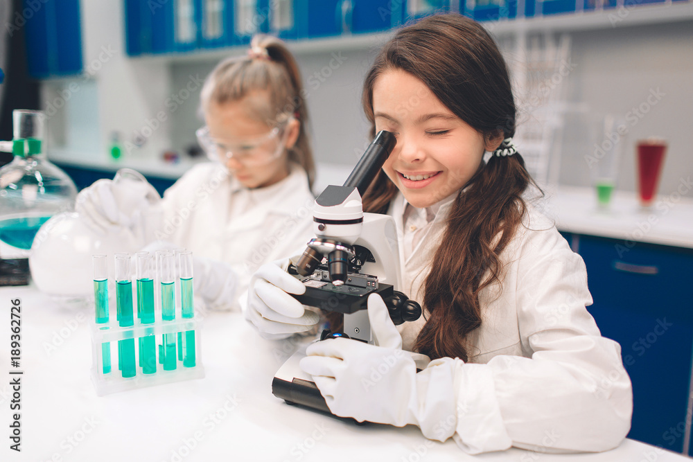 Two little kids in lab coat learning chemistry in school laboratory ...