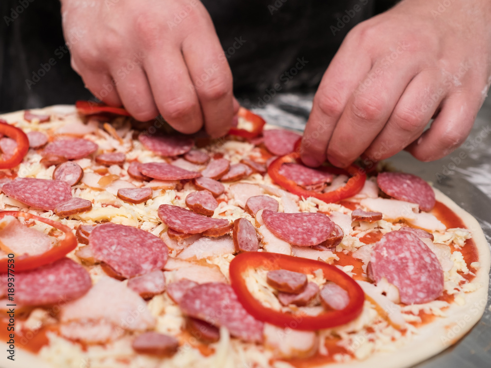 Chef cooking pepperoni pizza and adding ingredients on top. Simple yet ...
