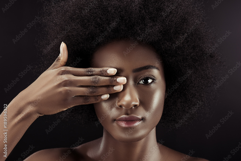 attractive african american woman covering eye with hand isolated on ...