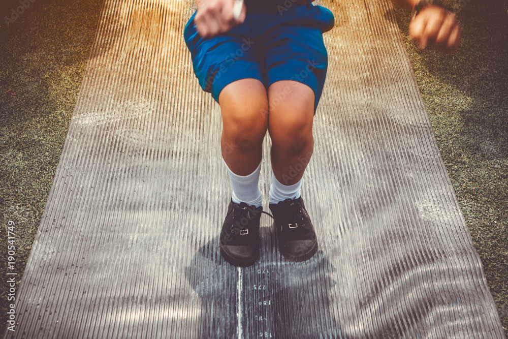 Students boy taking long jump on the rubber board during a school sport ...