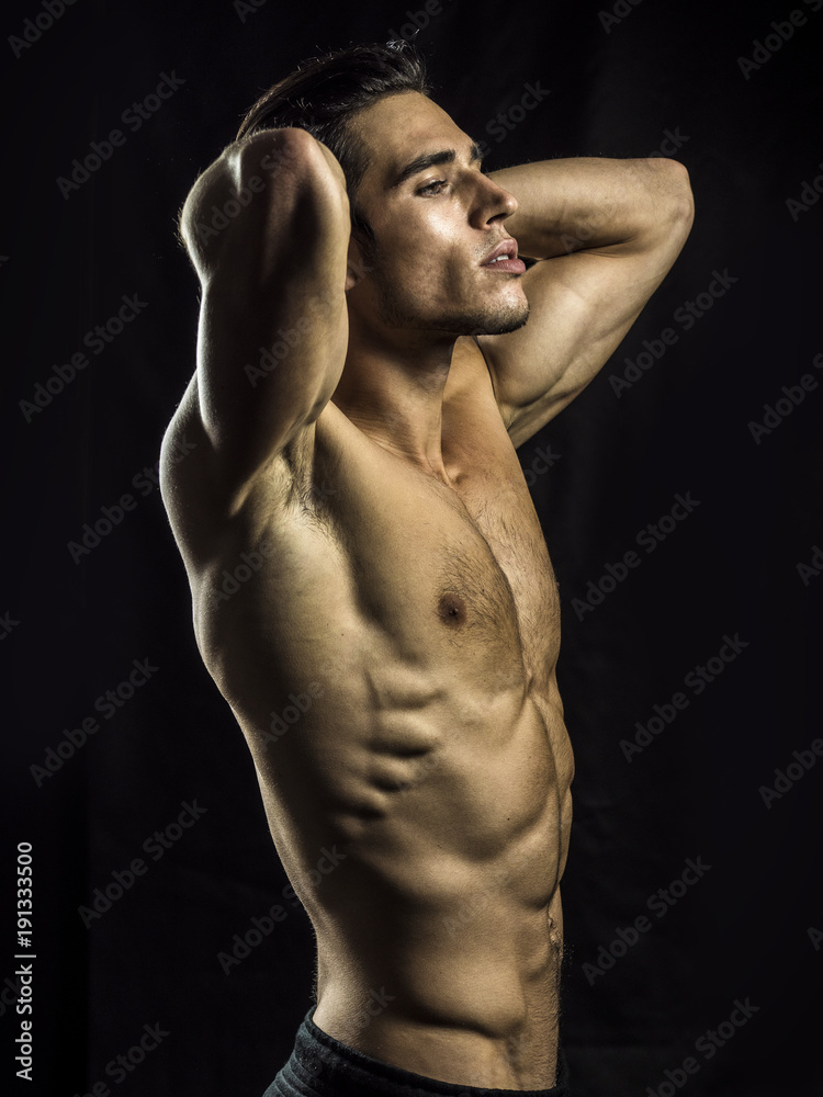 Handsome muscular shirtless young man standing confident, profile view ...