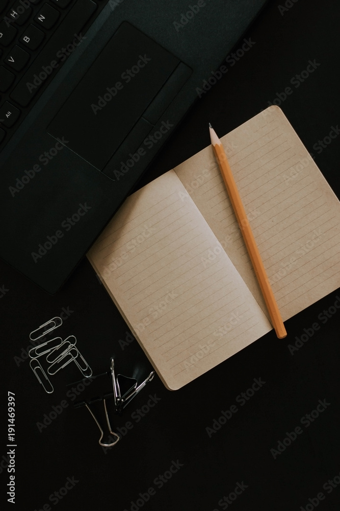 open diary with a pencil lies next to the laptop on black table Stock ...
