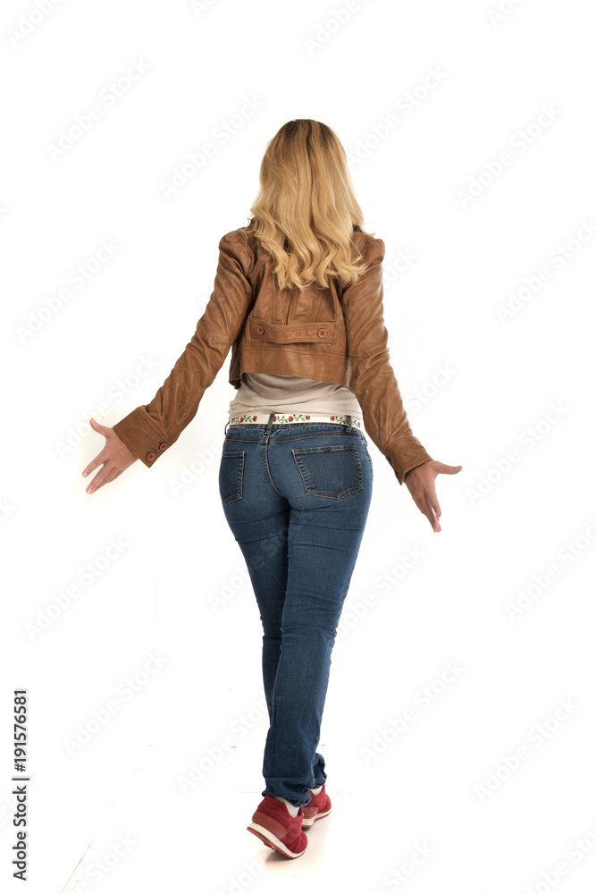 full length portrait of girl wearing brown leather jacket and jeans. standing pose facing away ...