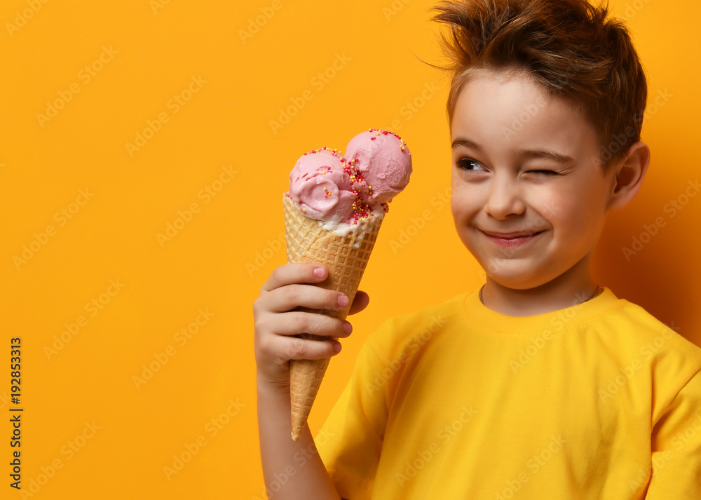 Baby boy kid eating strawberry ice cream in waffles cone and winking on ...