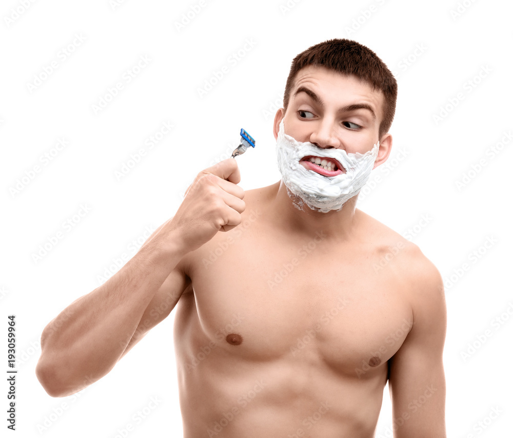 Emotional young man with shaving foam on his face holding razor against ...