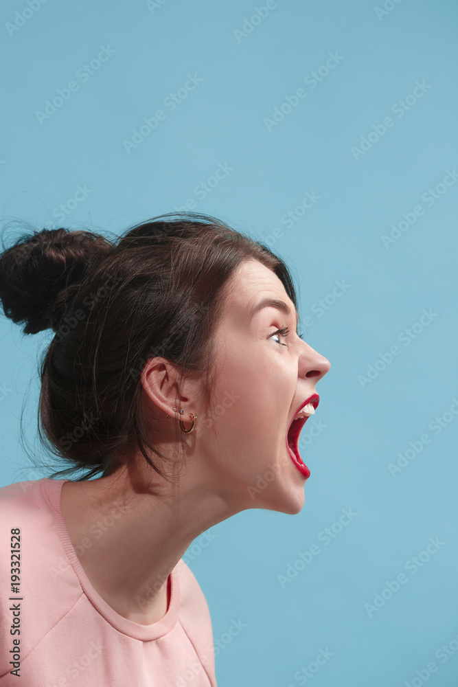 The young emotional angry woman screaming on blue studio background ...