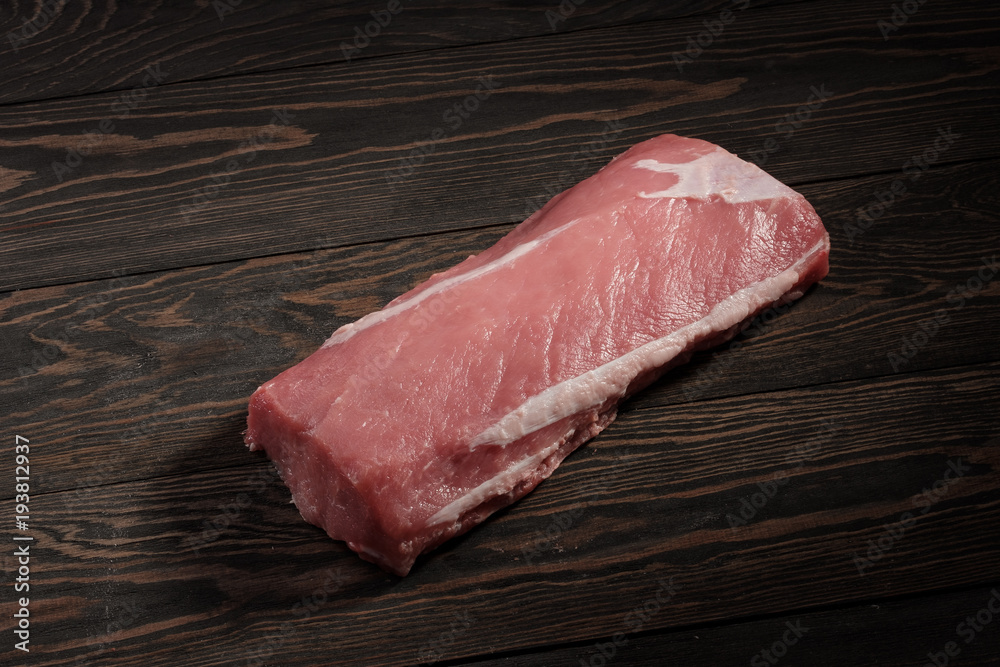 Whole boneless pork loin without fat. Pork tenderloin on a dark ...
