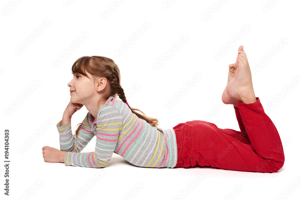 Side view of a child girl lying on front on the floor with crossed legs ...
