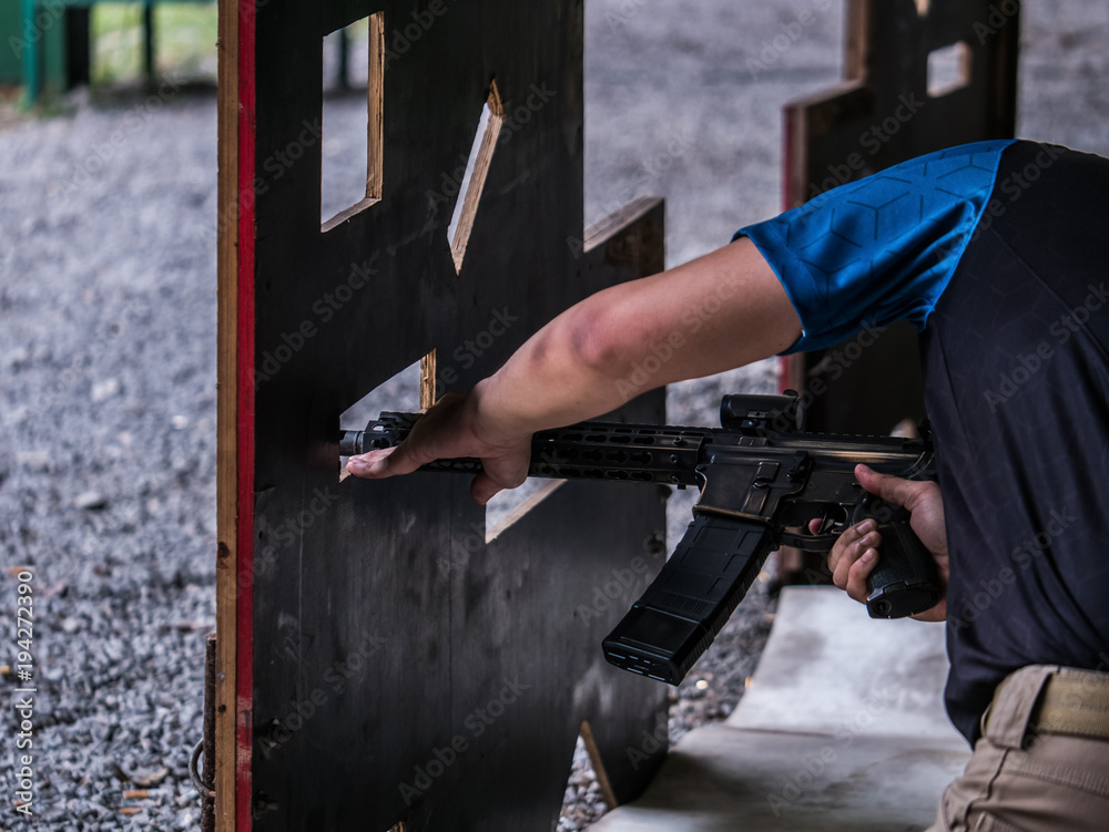 Male with rifle in hands aimimg target through one of the hole of VTAC ...
