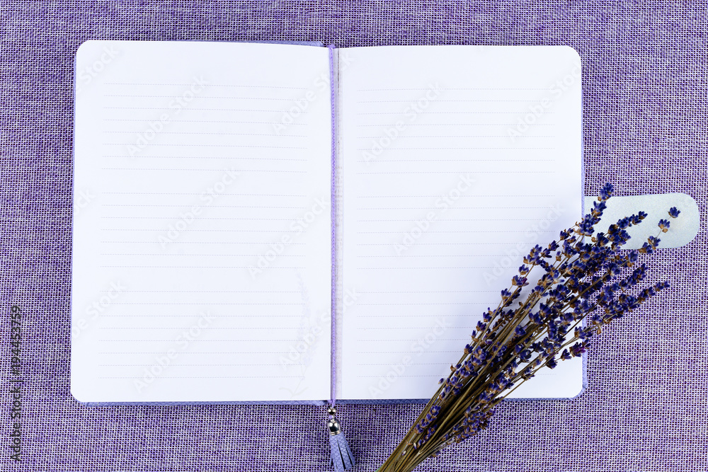 Purple notebook and flowers on purple background with copyspace, top ...