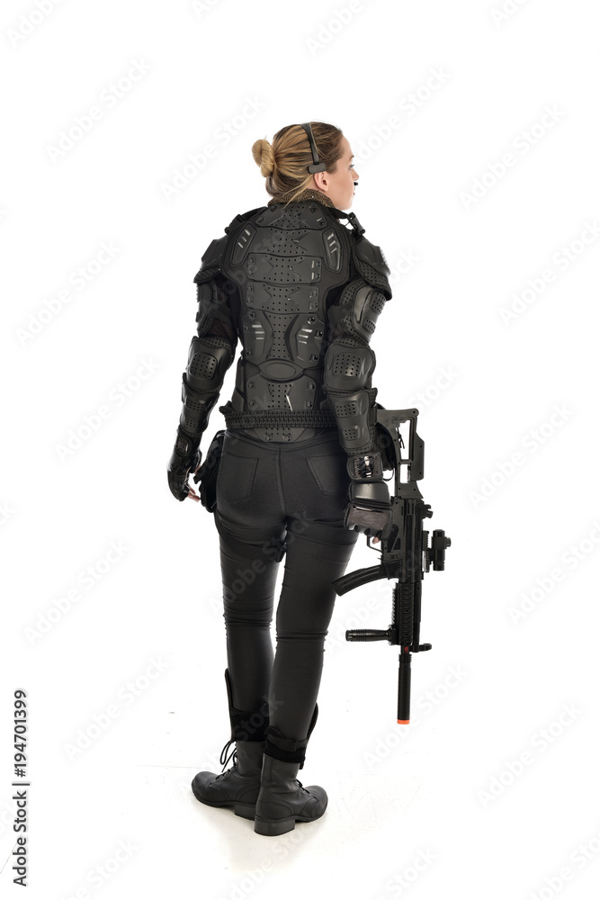full length portrait of female soldier wearing black tactical armour ...