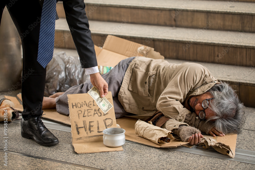 Businessmen's holding one dollar money gives to homeless person. Senior ...