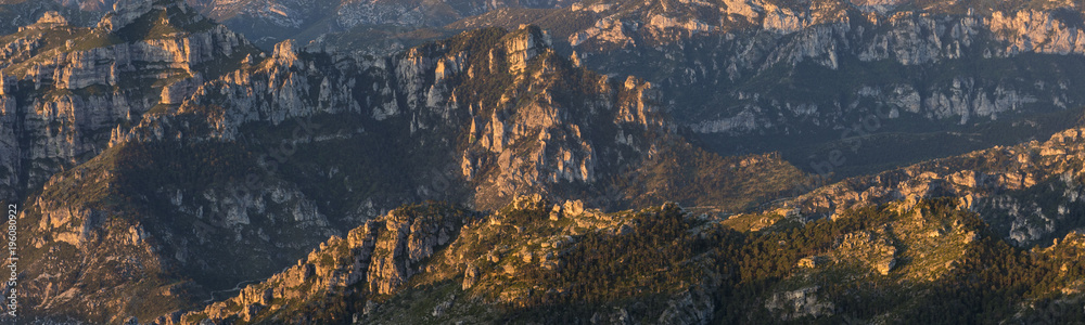 Panorama of the first morning light touching the rough rocky mountains ...