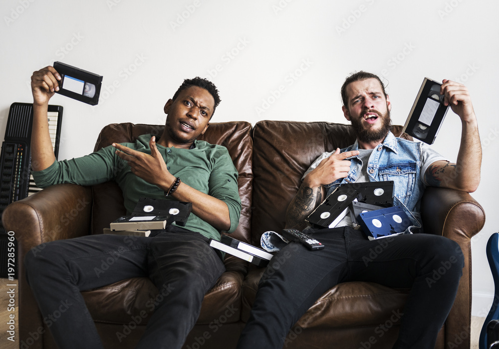African American male and a Caucasian male hipsters holding vintage VHS ...