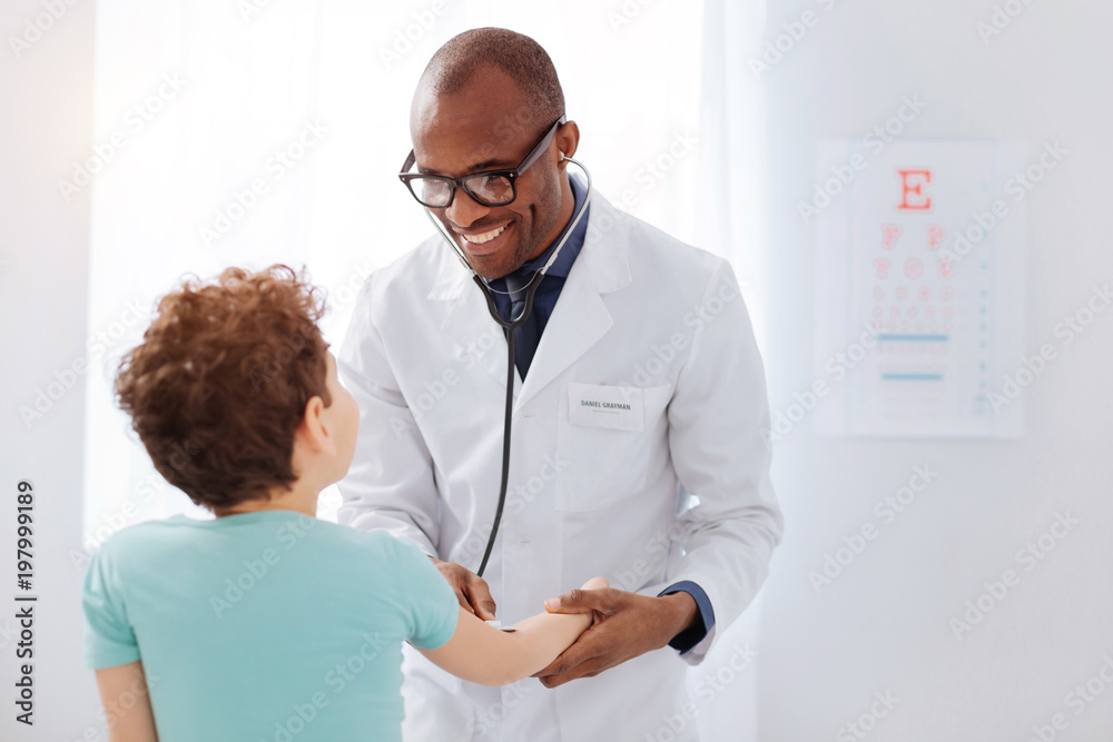 Physical examination. Jolly vigorous male doctor standing while using ...