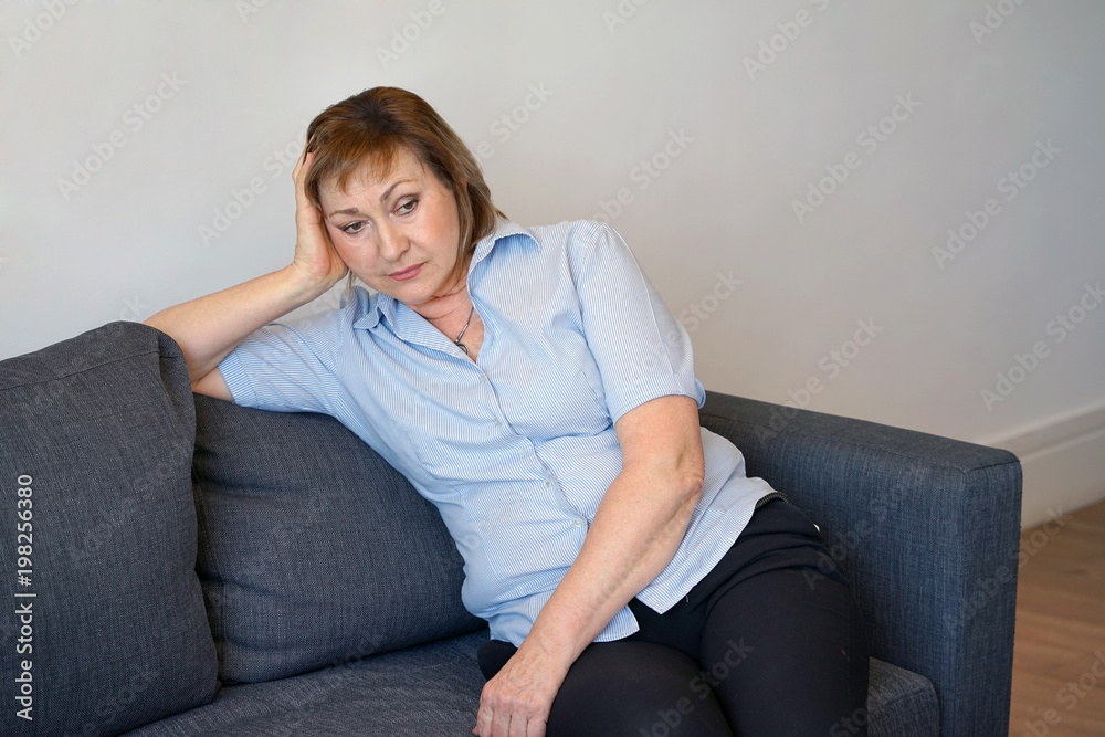 Loss of a loved one. Sadly depressed elderly woman at home, sitting on ...
