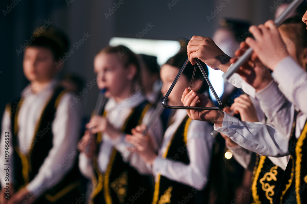 Photo Stock Little girl hands is playing on a musical triangle at stage ...
