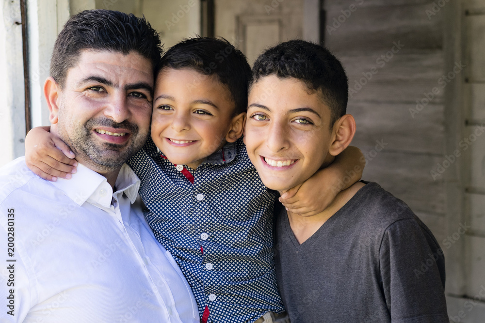 Outdoor portrait of a father and his sons. Father and older brother ...