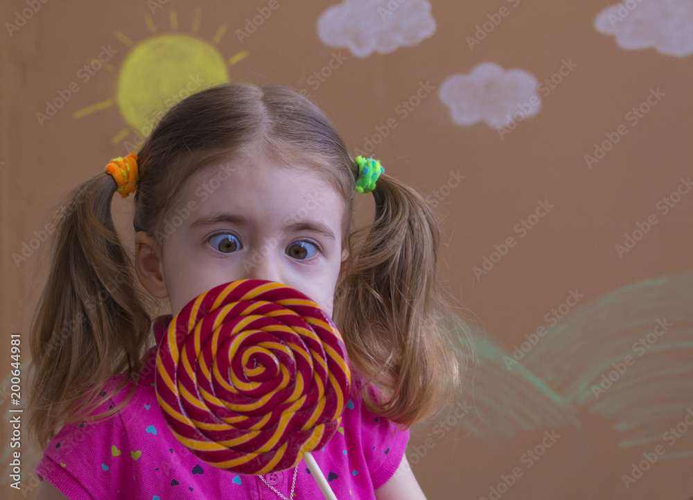 Funny child with candy lollipop, happy little girl eating big sugar ...
