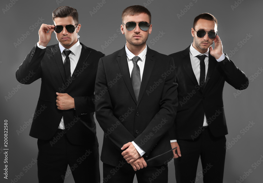 Handsome bodyguards on grey background Stock Photo | Adobe Stock