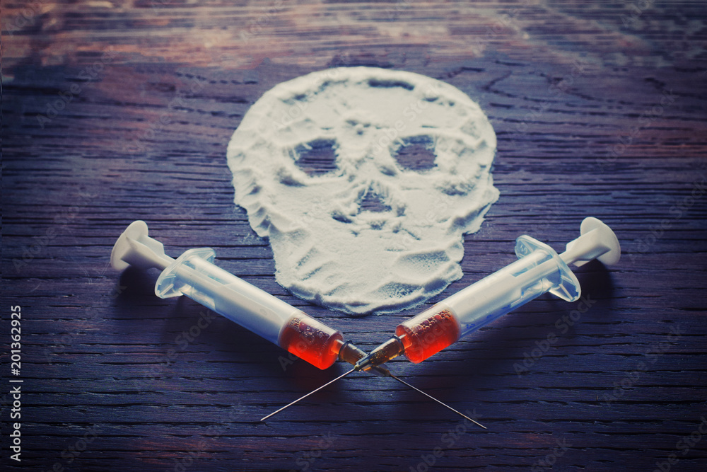 Narcotic powder in the form of a skull and syringes with injection. The ...