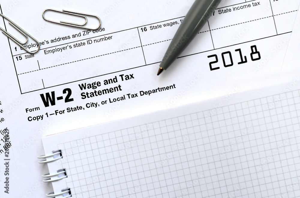 The pen and notebook on the tax form W-2 Wage and Tax Statement. The ...