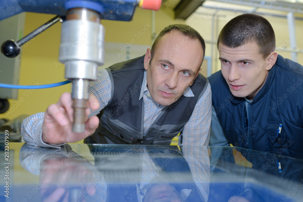 man teaching apprentice how to use machine on sheet glass Stock Photo ...