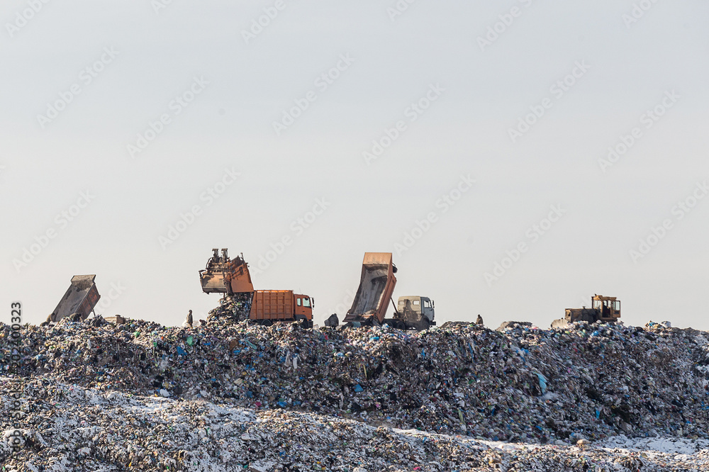 Dump trucks unloading garbage over vast landfill. Environmental ...