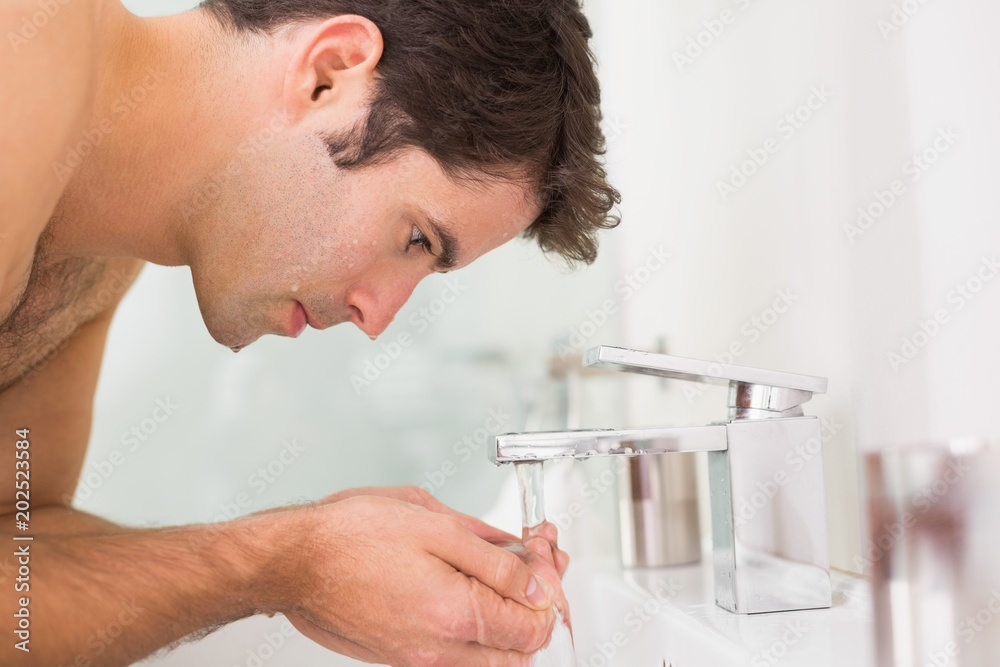 Shirtless young man washing face in bathroom Stock Photo | Adobe Stock