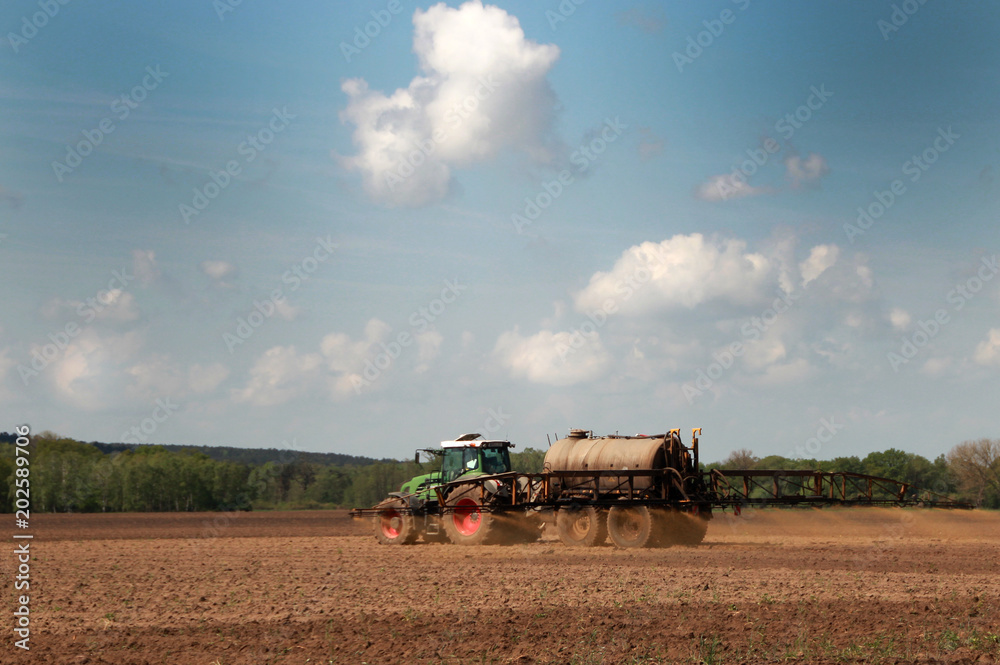 traktor mit tank und düngemaschine auf dem Feld Stock Photo | Adobe Stock
